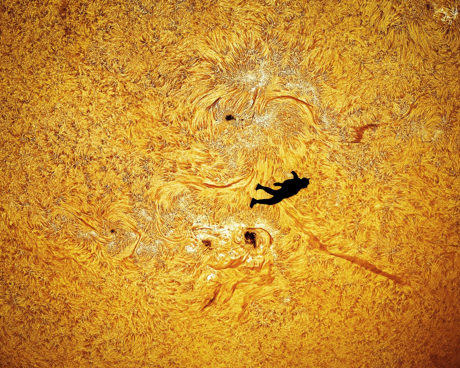 A skydiver's flight against the backdrop of the sun is captured in a photo